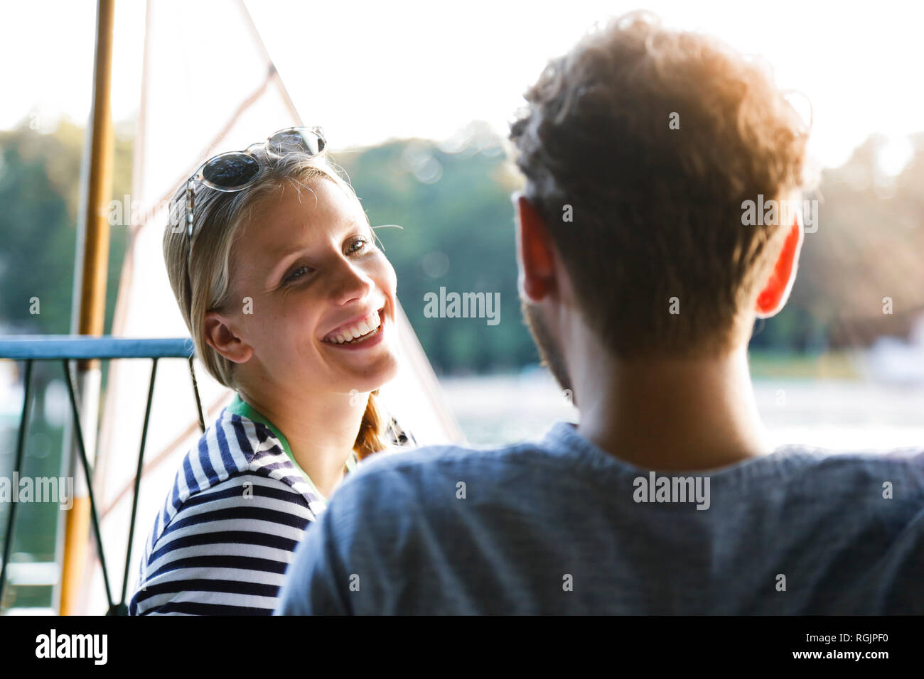 Young woman laughing at man at a lake next to sailing boat Stock Photo ...