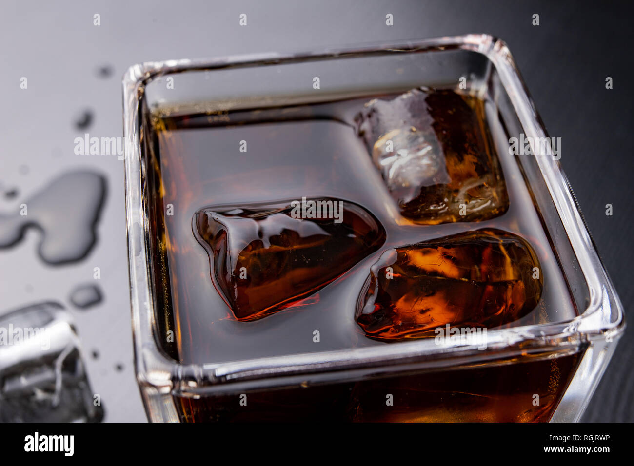 A cold drink with ice on a dark table. A chilled drink in a glass ...