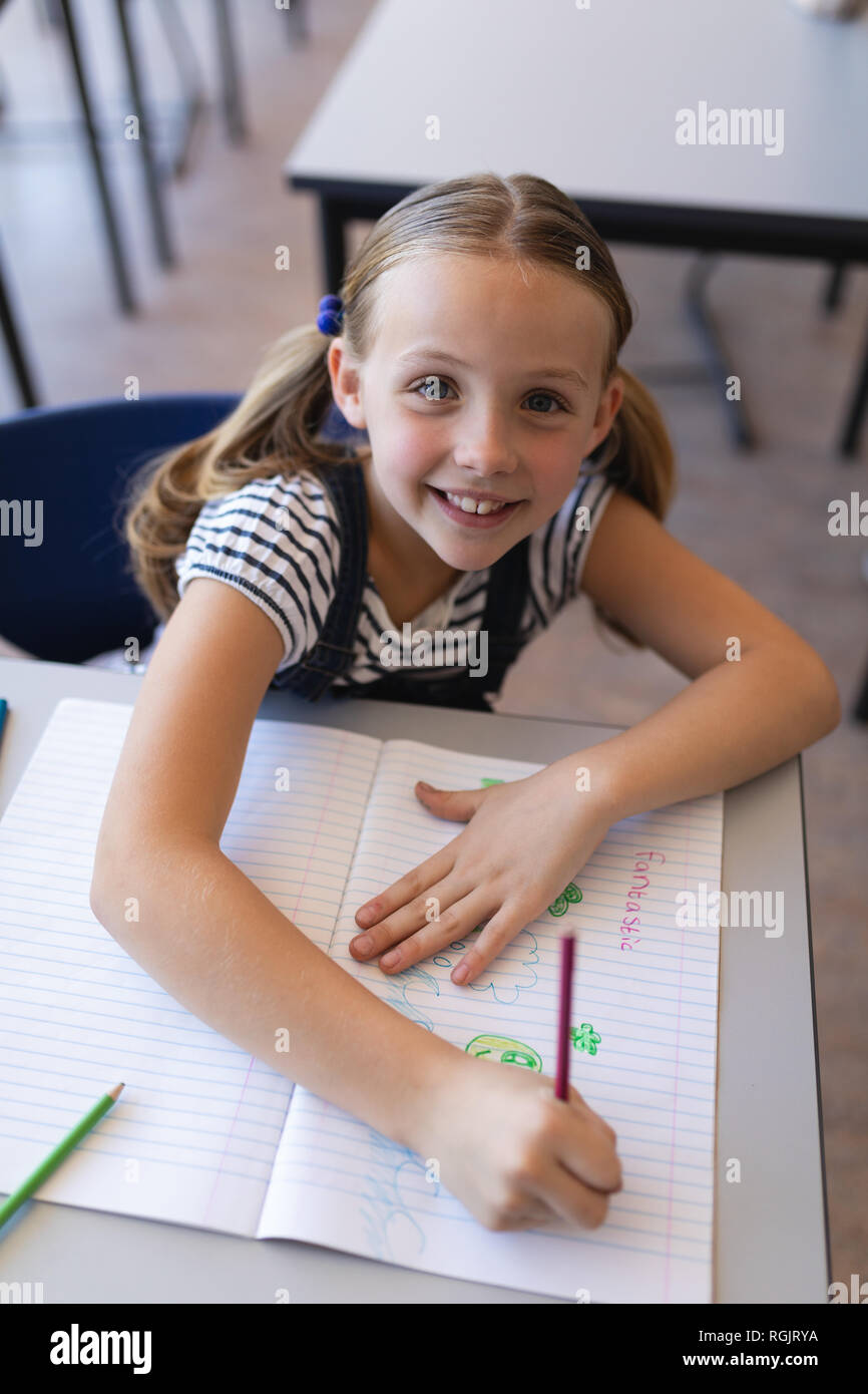 Schoolgirl looking at camera at desk in classroom Stock Photo - Alamy