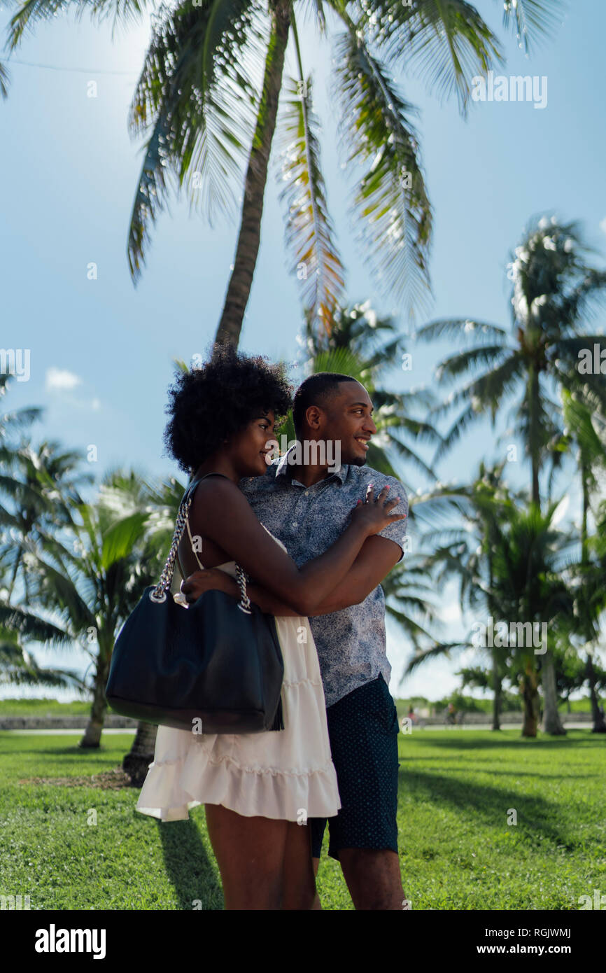 USA, Florida, Miami Beach, happy young couple embracing at palm trees ...