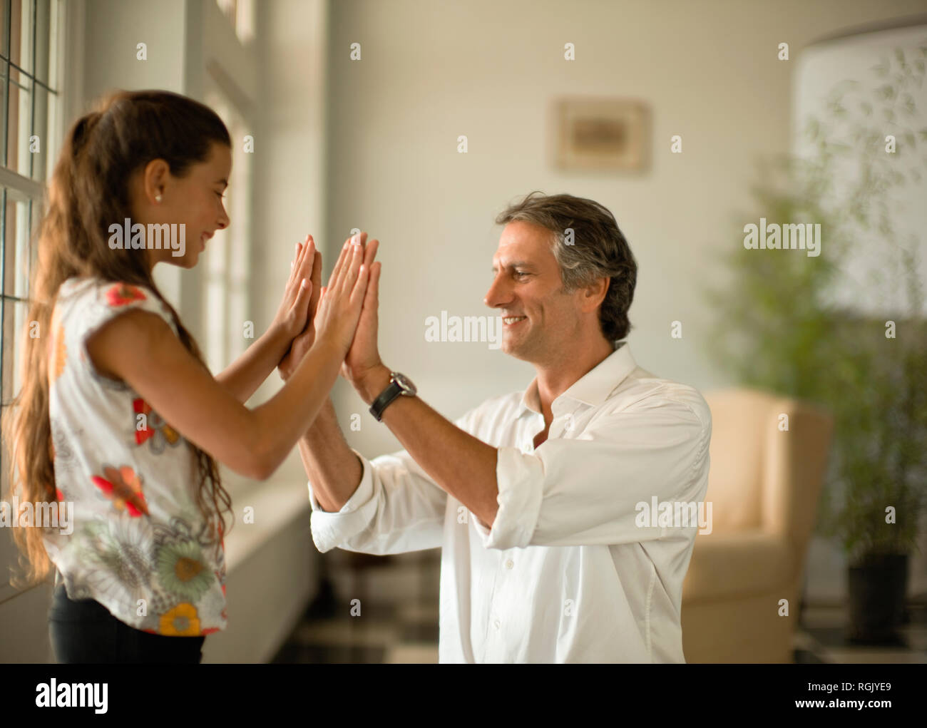 Middle aged father and his pre-teen daughter play a clapping game Stock ...