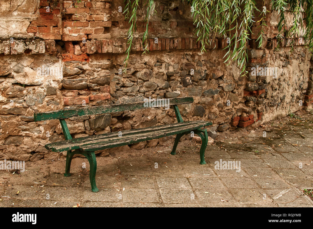 Old grunge wooden broken bench on decayed abandoned brick rural wall ...