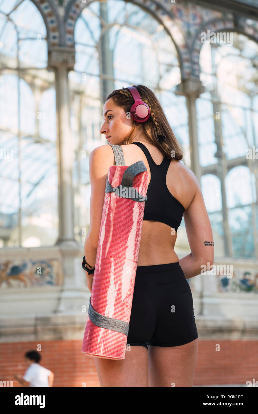Fit young woman carrying yoga mat, rear view Stock Photo - Alamy