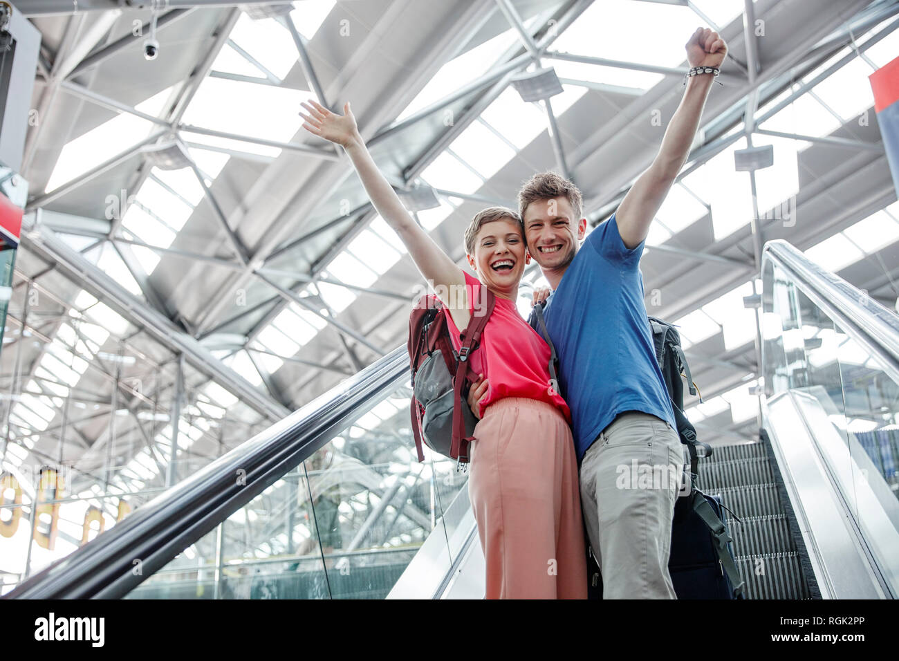 Happy couple cheering on escalator at the airport Stock Photo - Alamy