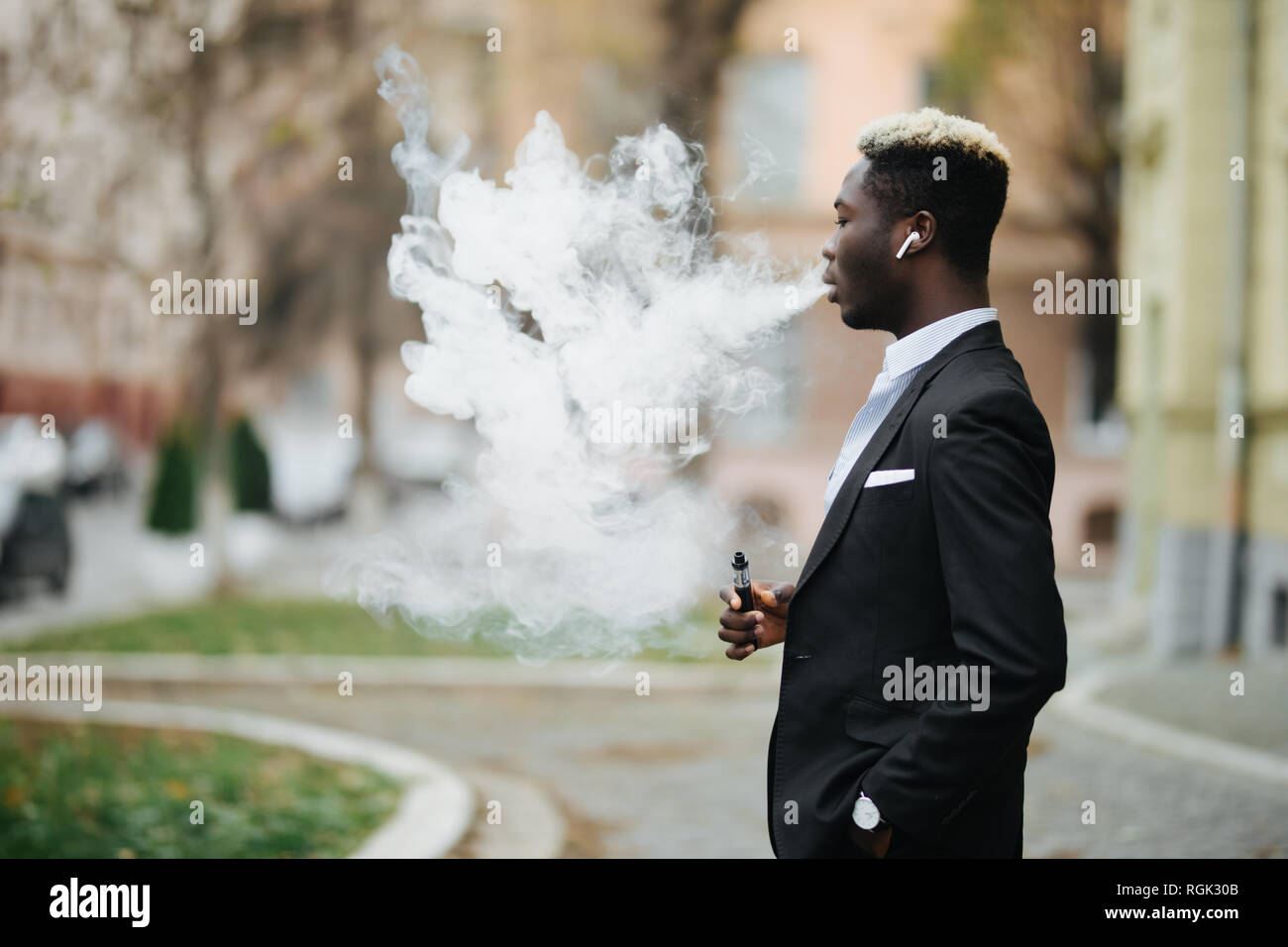 Portrait of a handsome young african man vaping an electronic cigarette ...