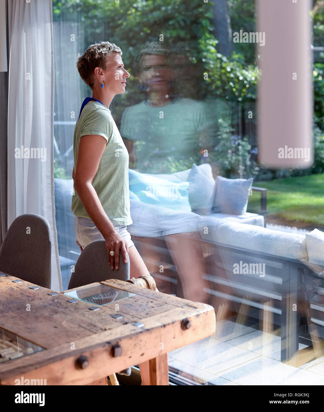 Woman looking out of window Stock Photo - Alamy
