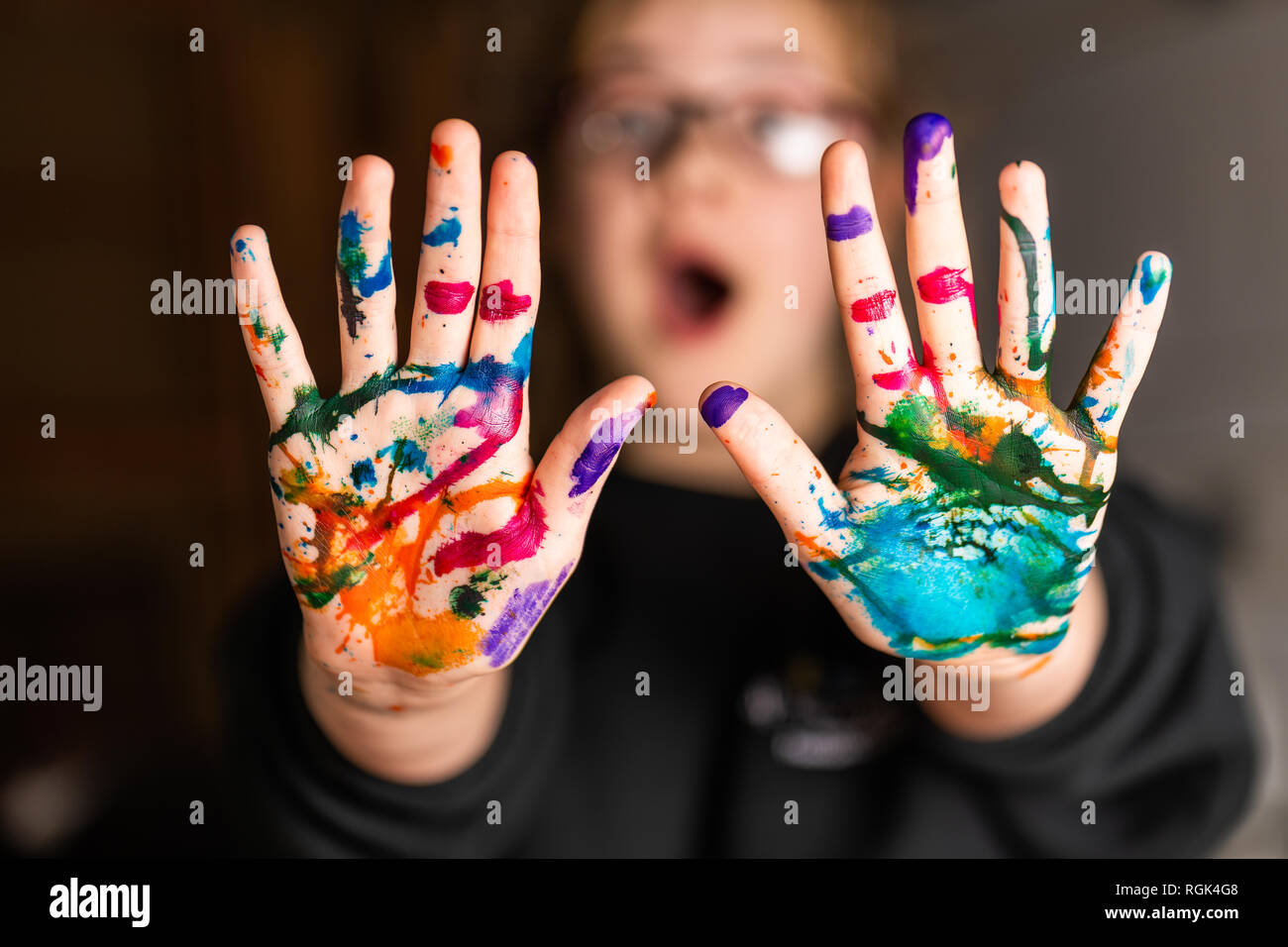 A child looks happy or surprised as her hands are covered in red, pink ...