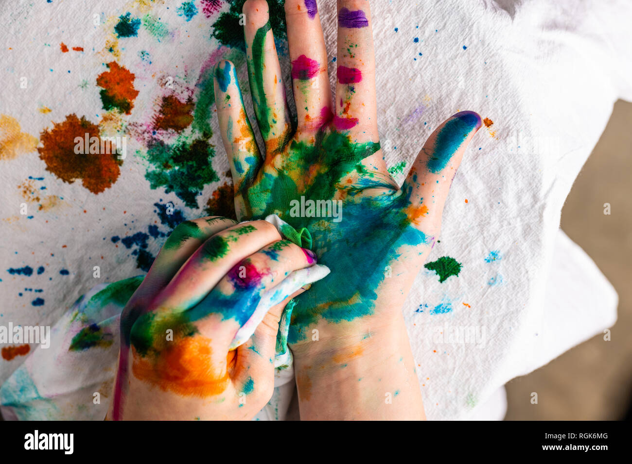 A child cleans up hands that are covered in red, pink, yellow, orange ...