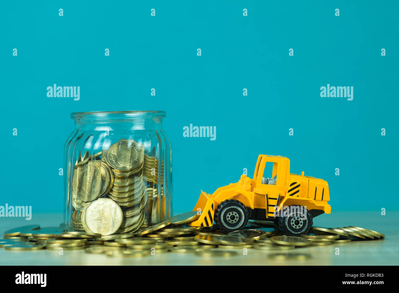 Mini bulldozer truck loading stack coin with pile of gold coin to glass ...