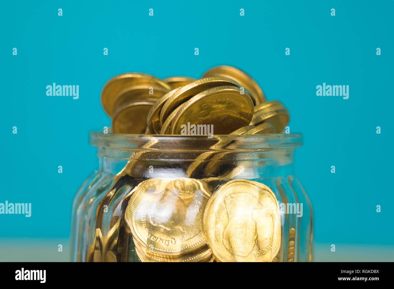 Coin money in the glass jar on table with green background, for saving ...
