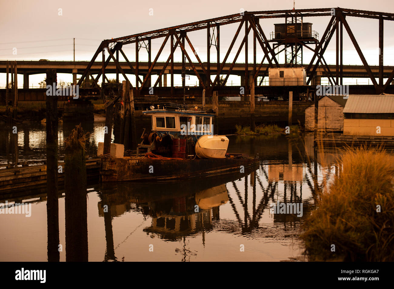 Old abandoned tug boat in industrial marina with train trestle in ...