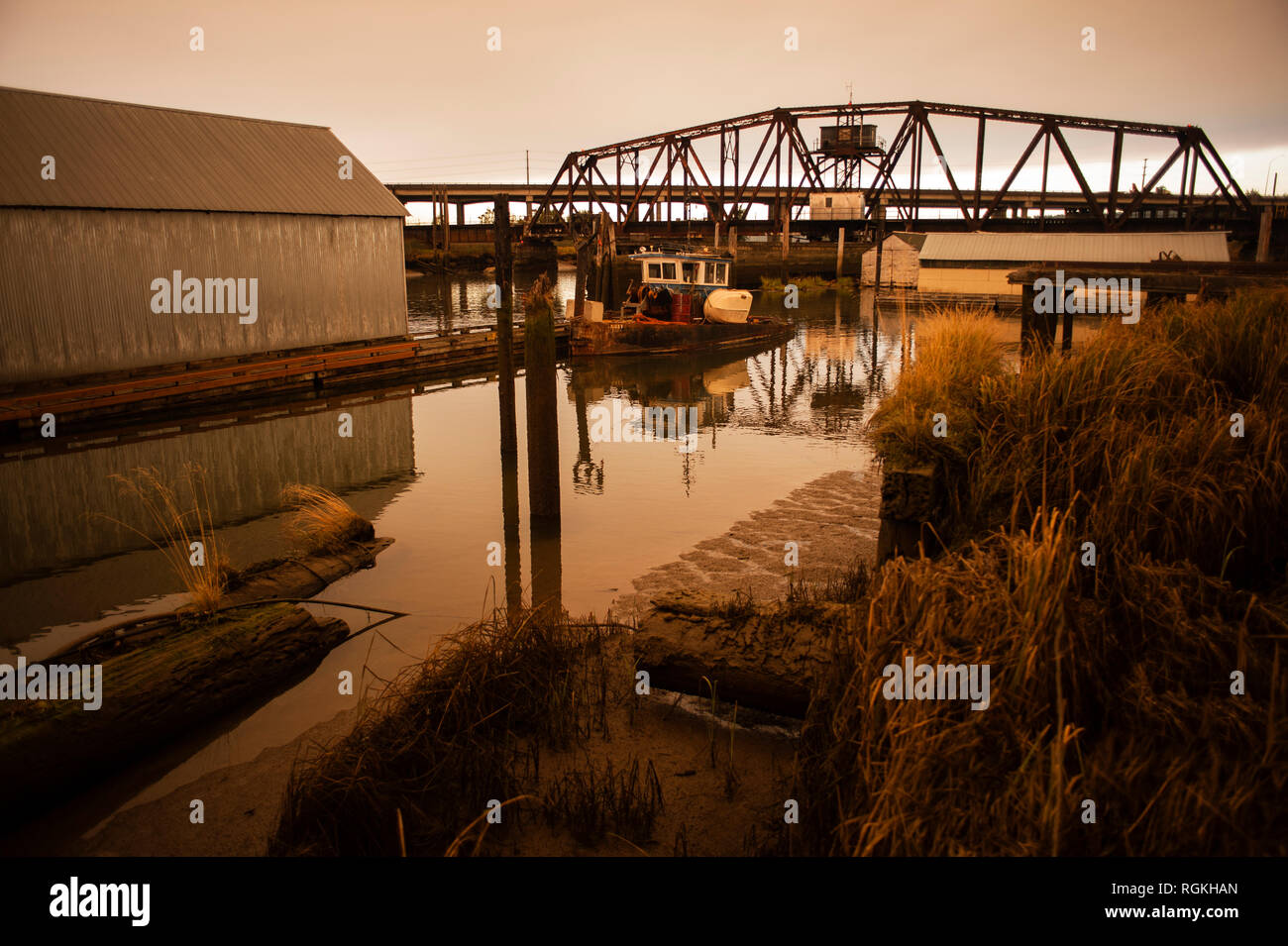 Old abandoned tug boat in industrial marina with train trestle in ...