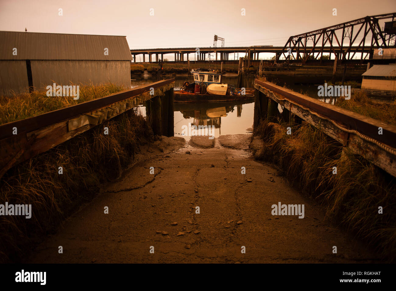 Old abandoned tug boat in industrial marina with train trestle in ...