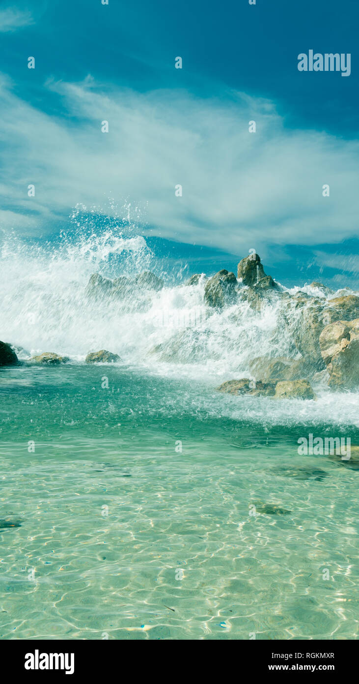 Beautiful turquoise water in a still lagoon as waves crash over a rock ...