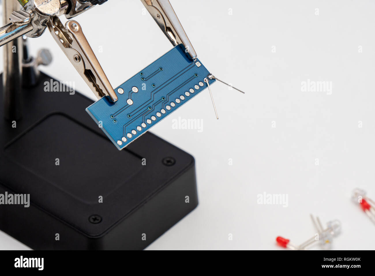 Blue circuit board in soldering helping hands before technological ...