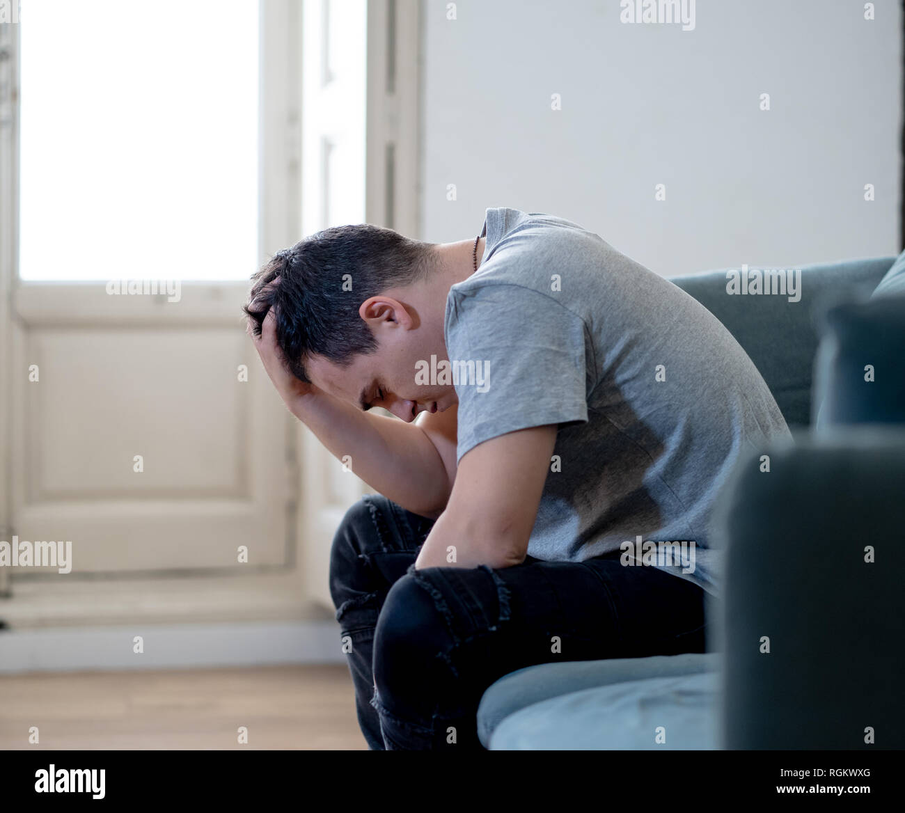Unhappy depressed caucasian male sitting crying and lying in living ...