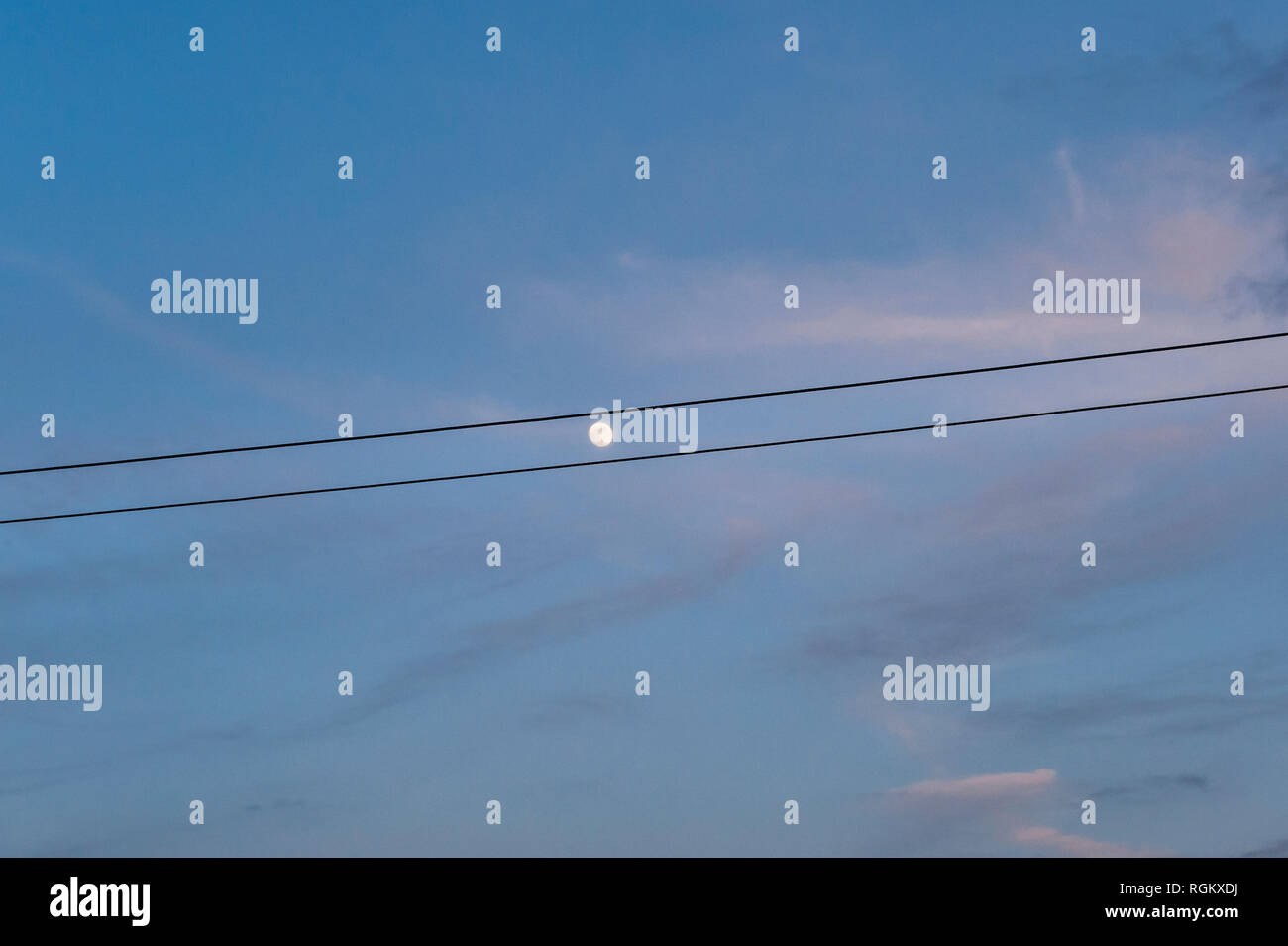 UK. A full moon appears as if held between two telephone (telegraph ...