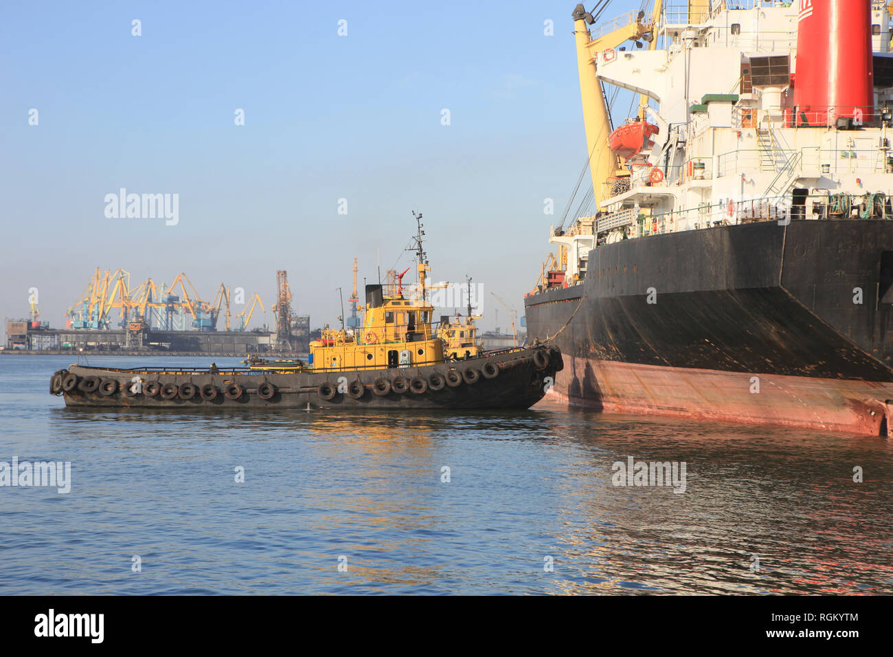 Tug ship directs cargo ship Stock Photo - Alamy