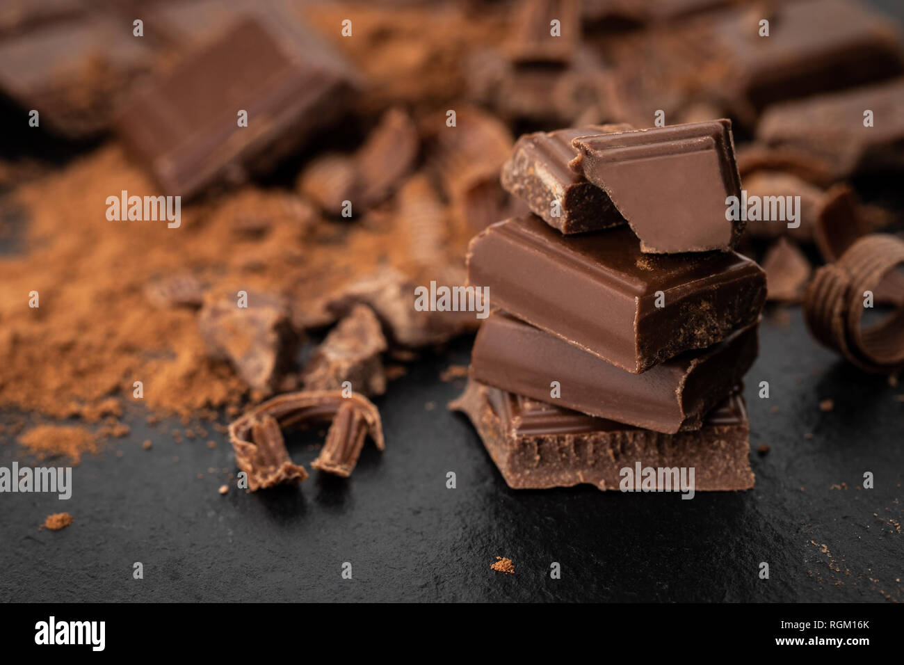 Broken chocolate pieces and cocoa powder on a dark background Stock ...