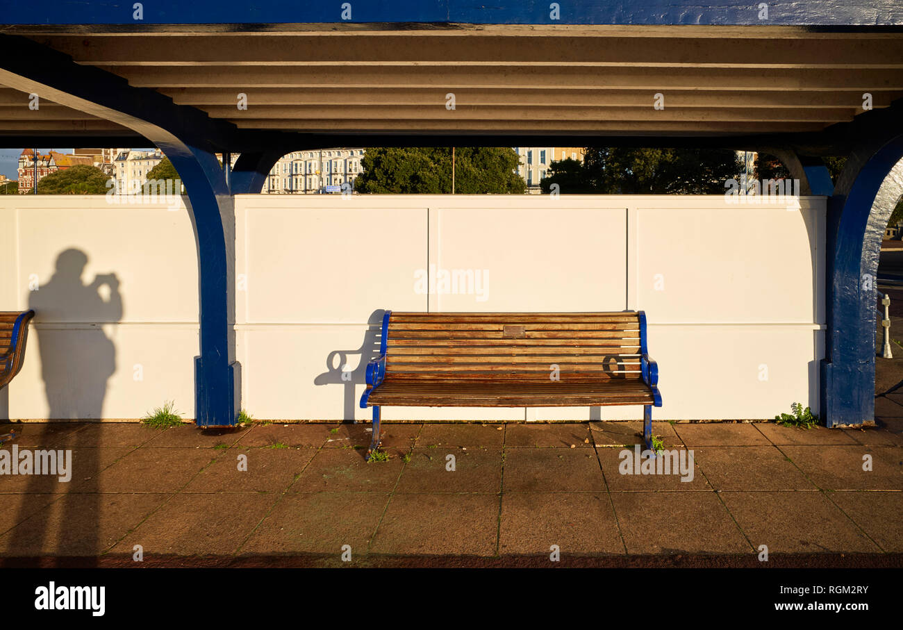 Photographers shadow in a picture of a seaside bench early on a winter ...