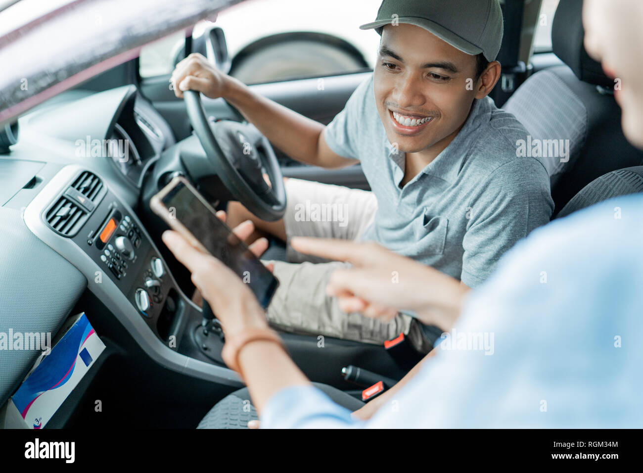 man driver looks passenger smartphone's to approved a new destination ...
