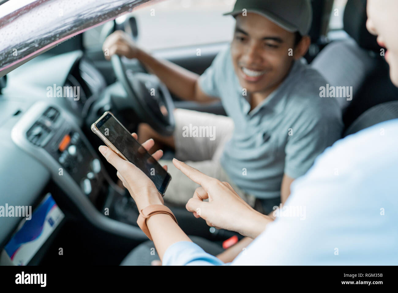 portrait of passenger showing his smartphone application to the driver ...
