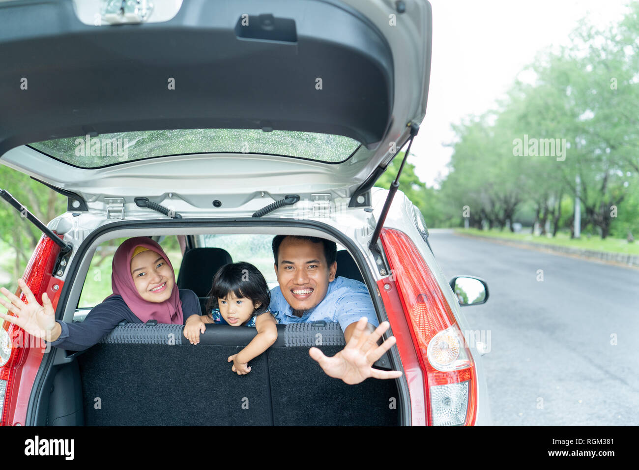 mother, father, and his daughter inside a car look out from back ...