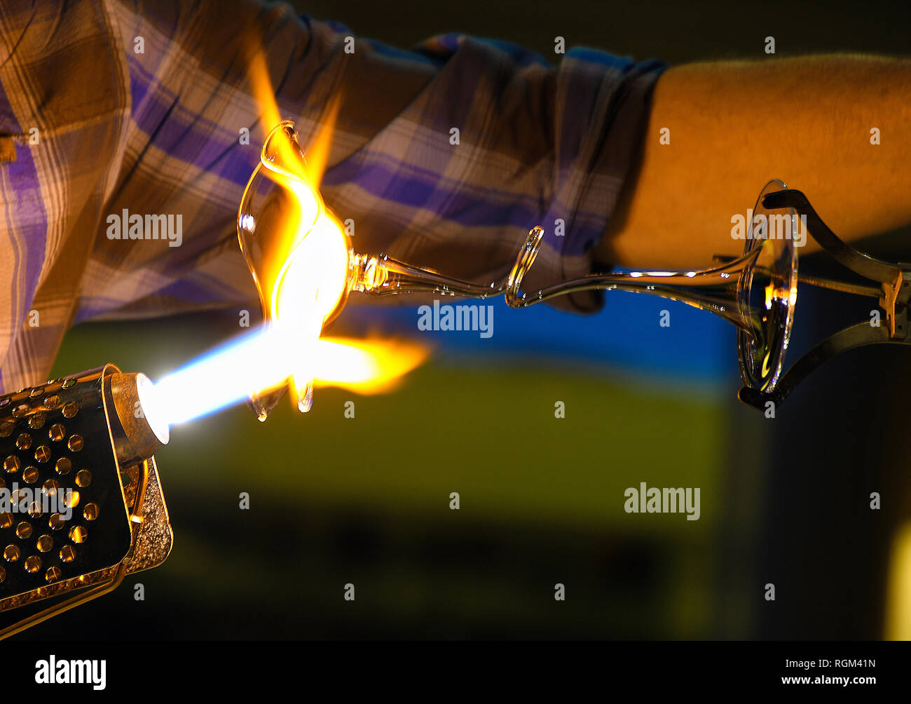 close up of glass blower making fancy glass vase with flaming torch ...