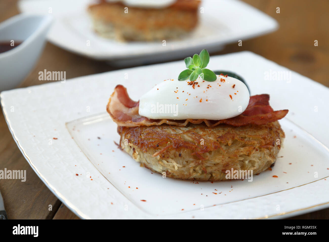 Potato rosti, poached egg and bacon on top Stock Photo - Alamy