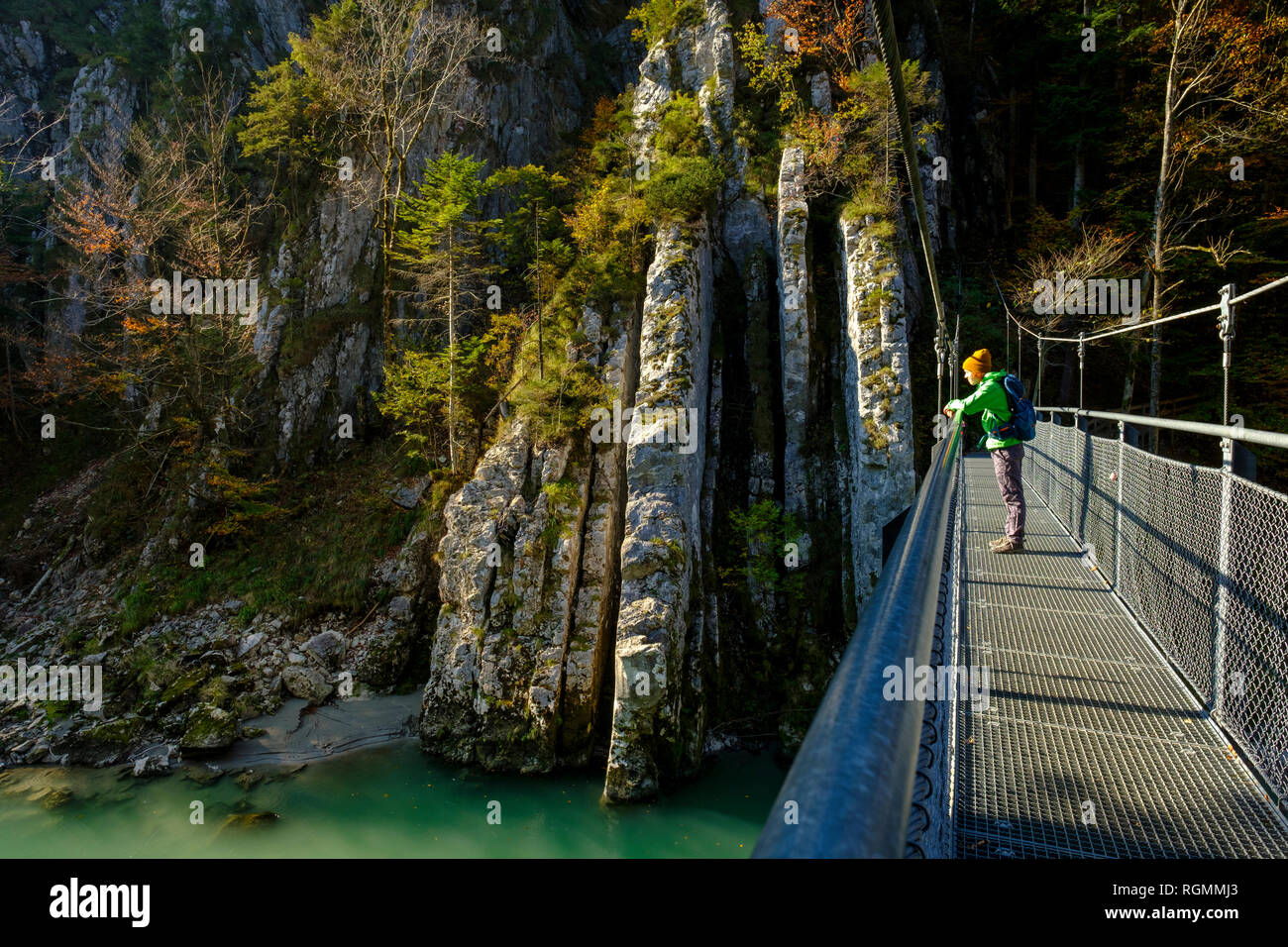 Austria, Tyrol, hiker on suspension bridge looking at Tiroler Ache in ...