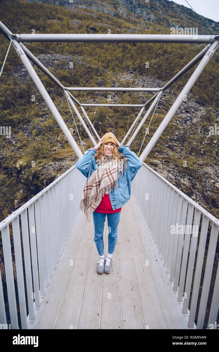 Young woman standing on a windy bridge, holding her cap Stock Photo - Alamy