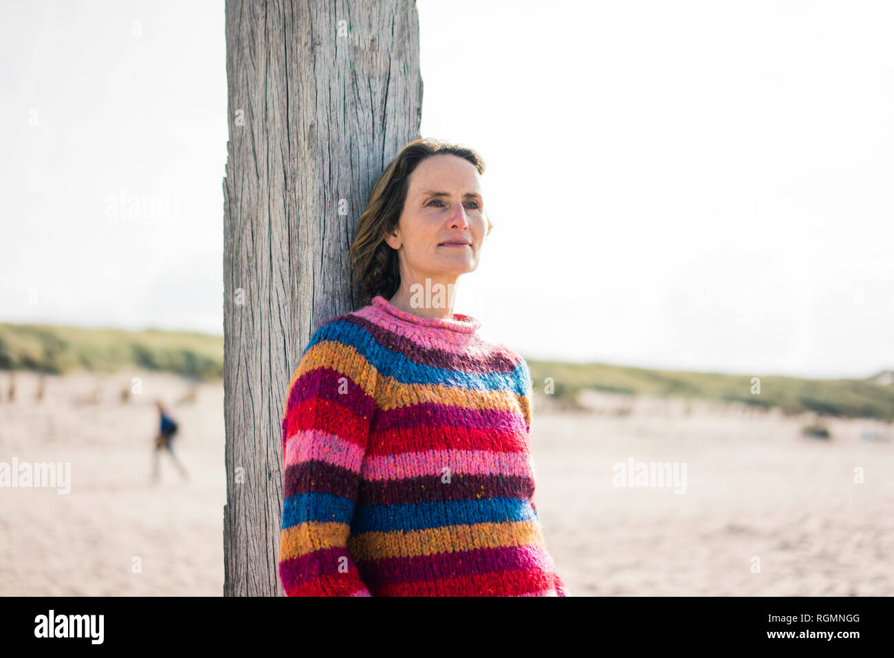 Mature woman relaxing on the beach, leaning on a pole Stock Photo - Alamy