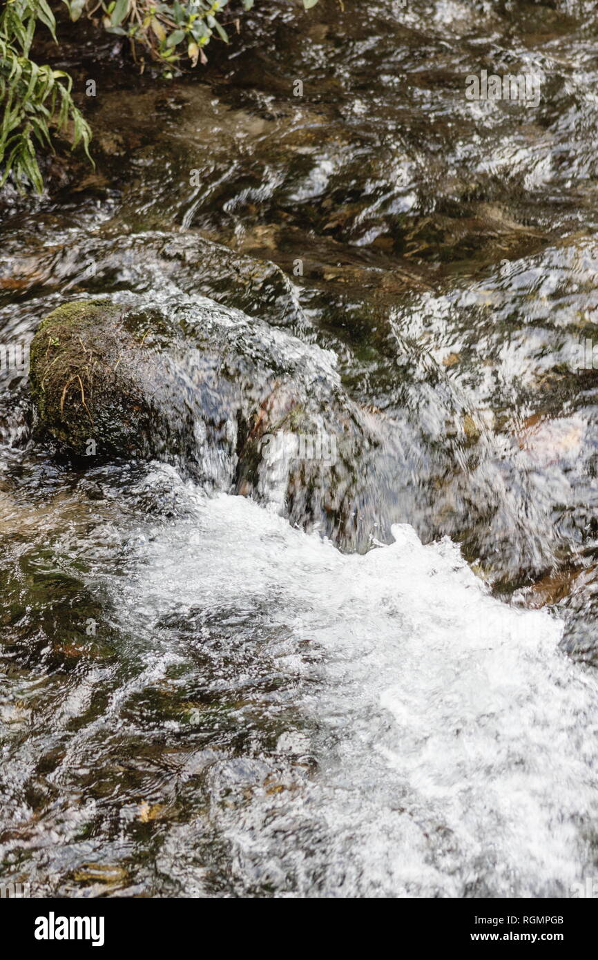 Background image of running fresh water in a river over riverstones ...