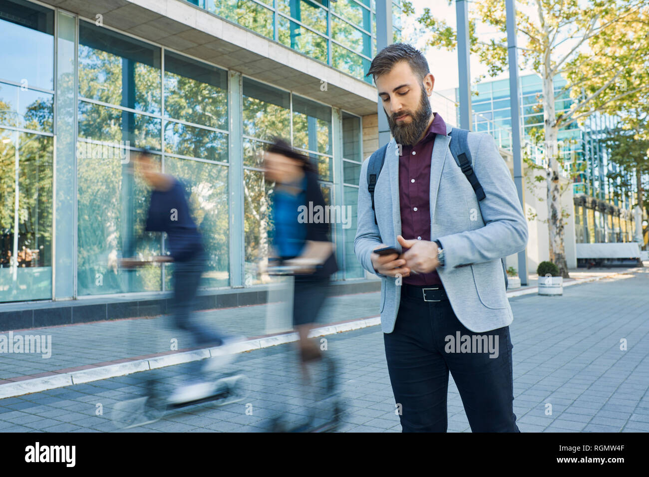 Businessman using cell phone with commuters riding on scooters Stock ...