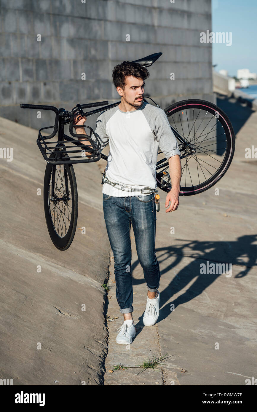 Young man carrying commuter fixie bike at concrete wall Stock Photo - Alamy