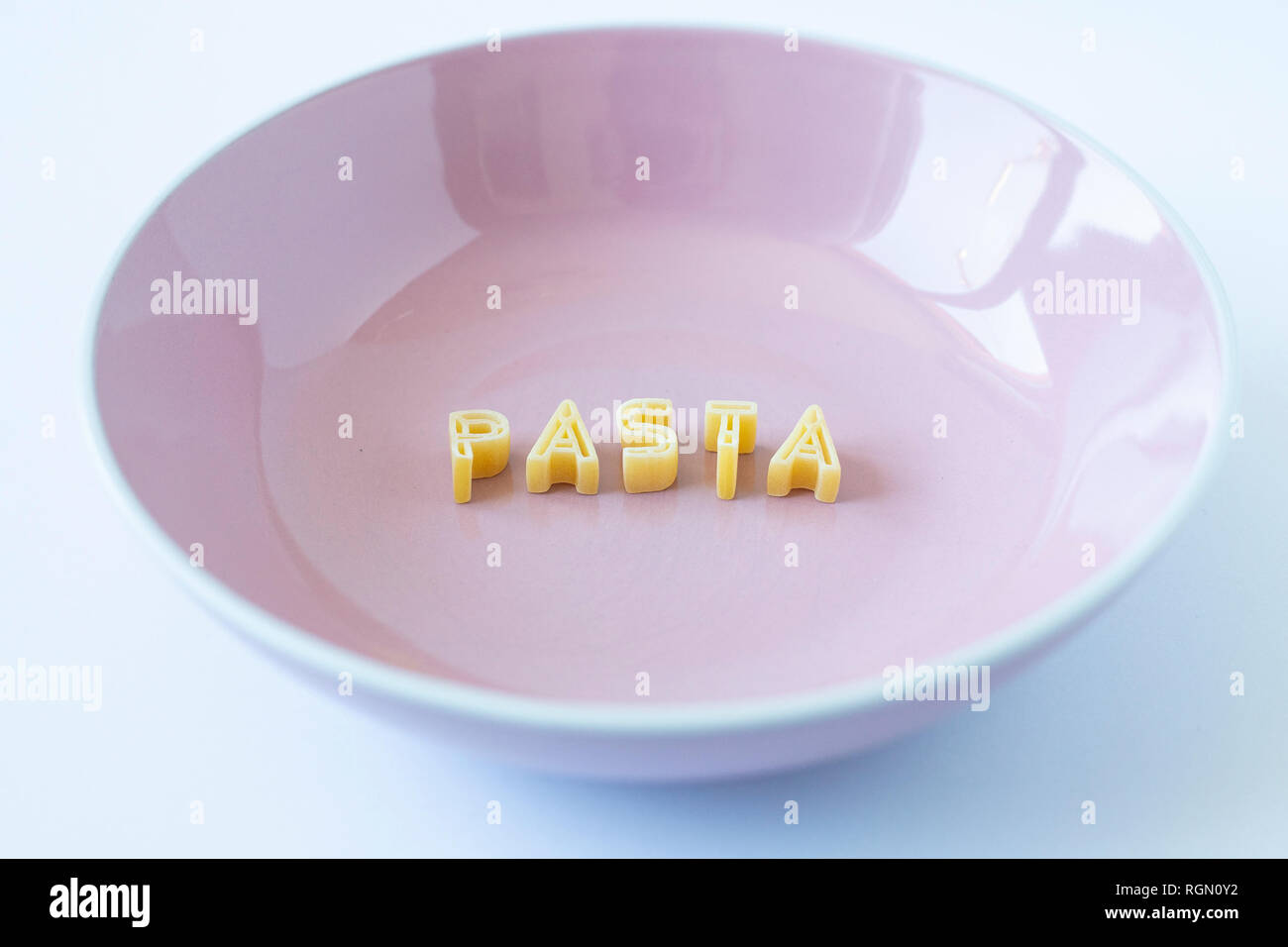 The word "pasta" composed with real pasta letters in a pink dish. Side ...