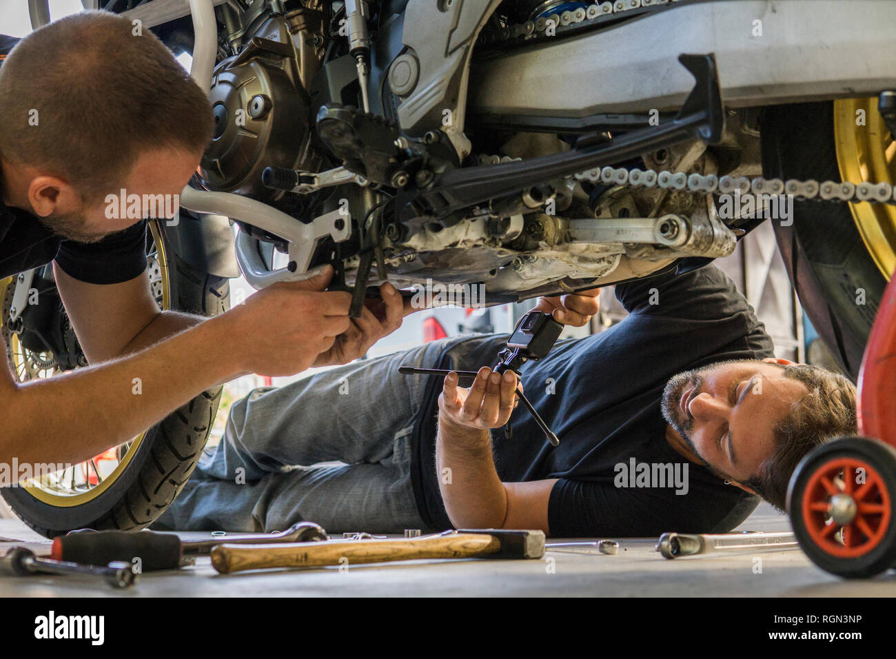 Mechanic working on motorcycle in workshop filmed by his partner Stock ...