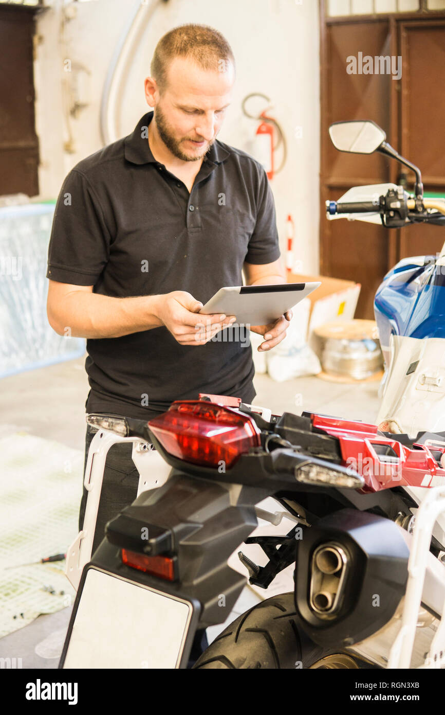 Man using tablet next to motorcycle workshop hi-res stock photography ...