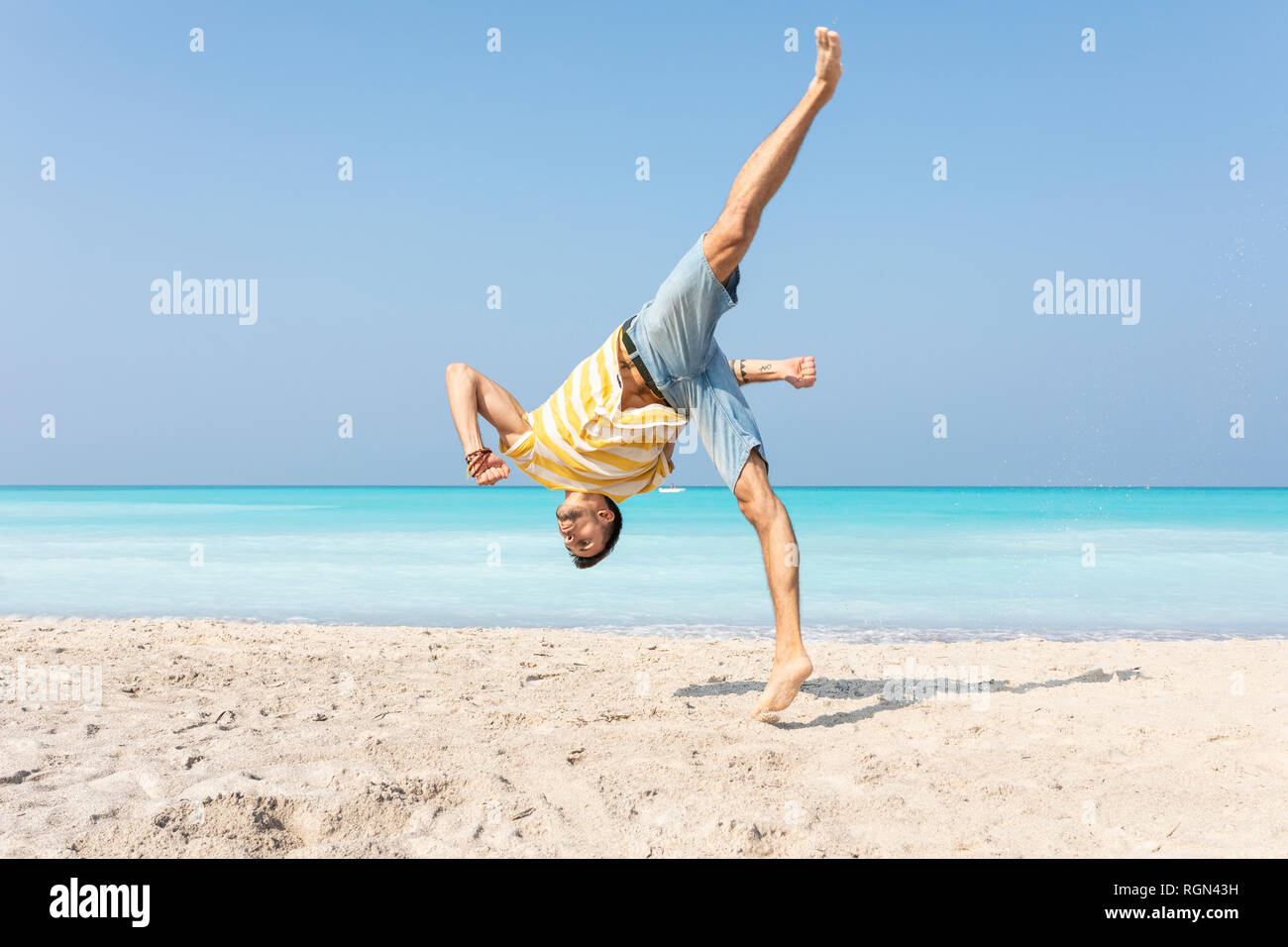 Young man doing a somersault on the beach Stock Photo - Alamy