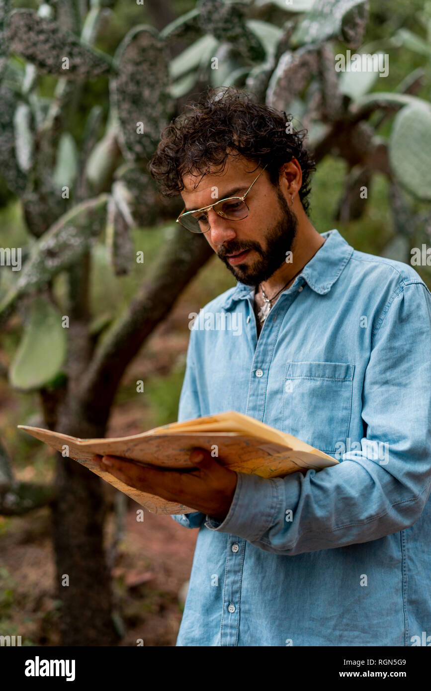 Young man standing in nature, looking at map Stock Photo - Alamy