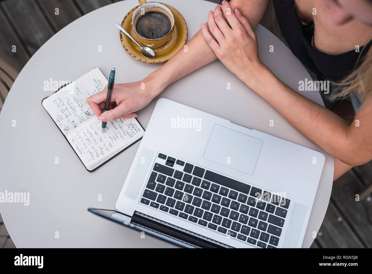 Young woman sitting on balcony with laptop taking notes, top view Stock ...