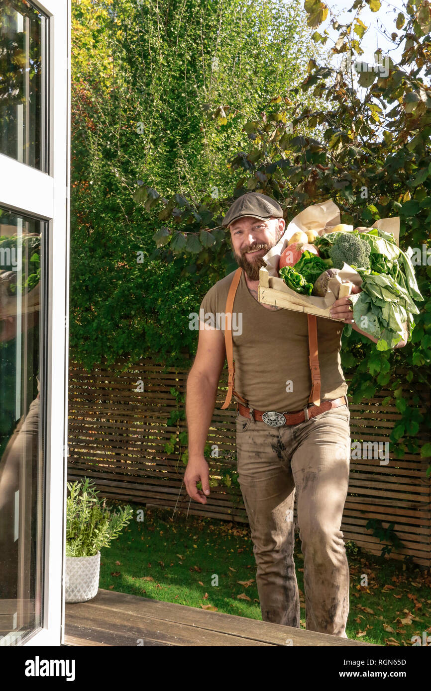Mature man carrying crate with vegetables in his garden Stock Photo - Alamy