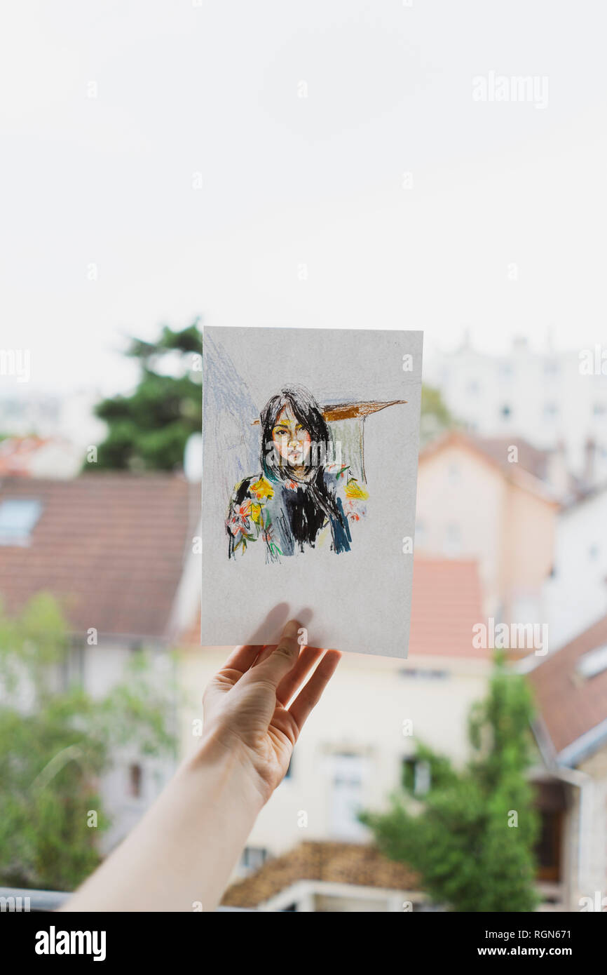 Woman's hand holding drawing of female portrait Stock Photo - Alamy