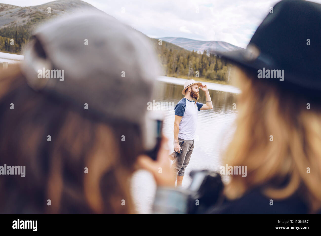 Sweden, Lapland, back view of two women taking photo of man Stock Photo ...