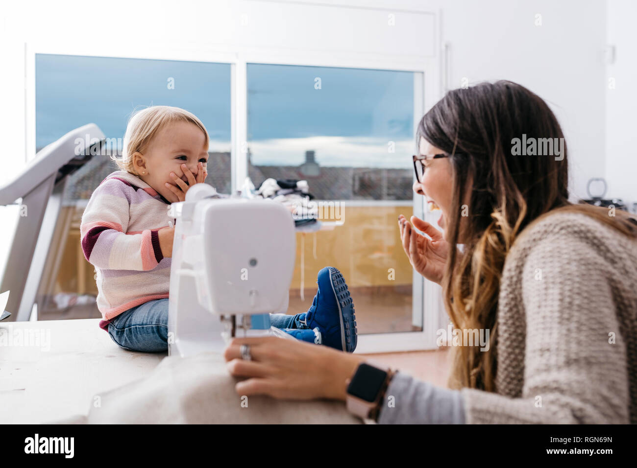 Happy mother with little daughter at home using sewing machine Stock ...