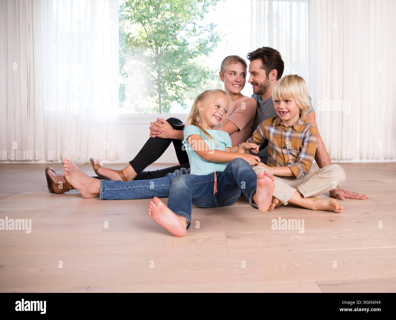 Relaxed family sitting on the floor at home Stock Photo - Alamy