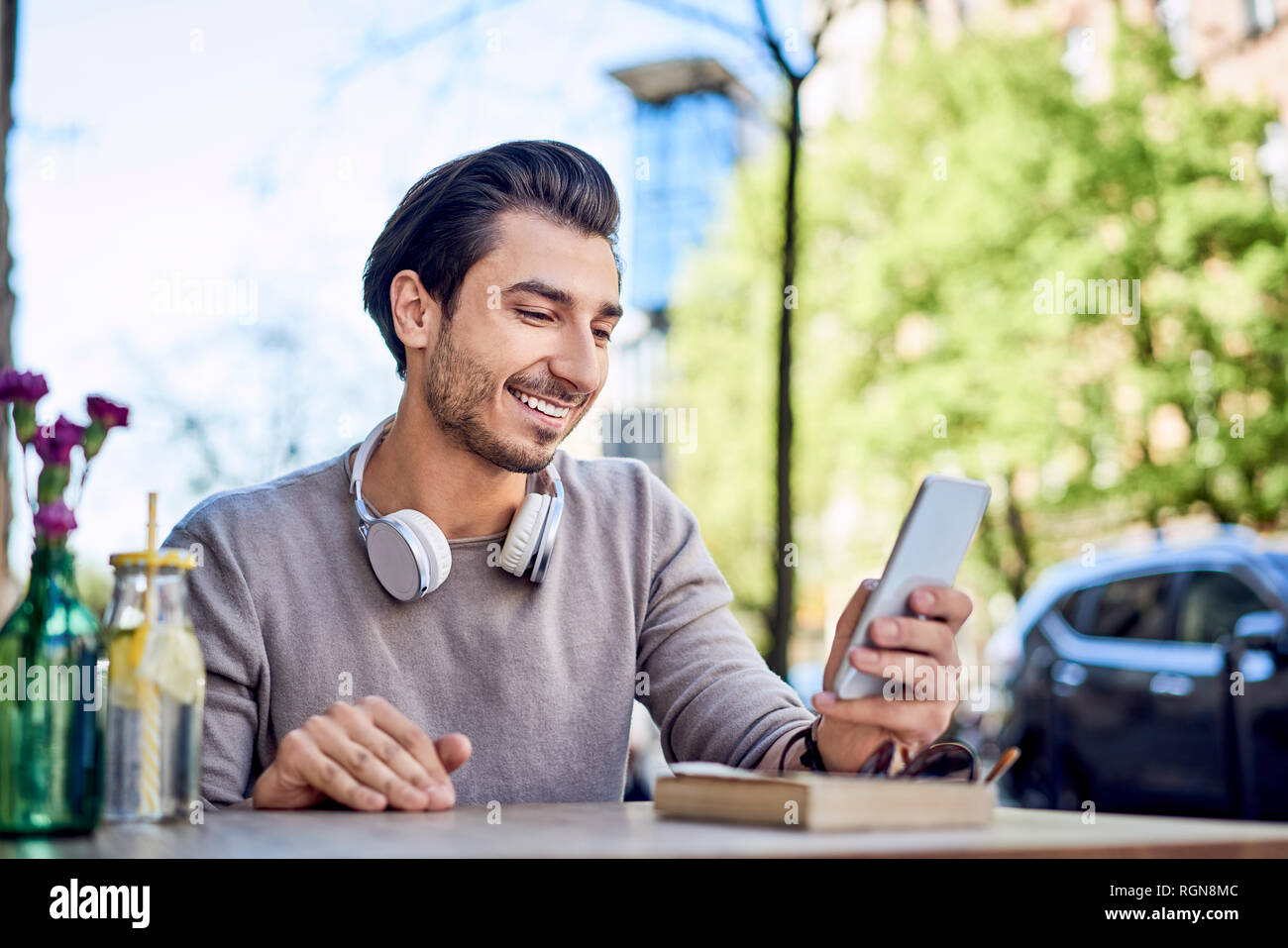Happy young man using cell phone at outdoors cafe Stock Photo - Alamy