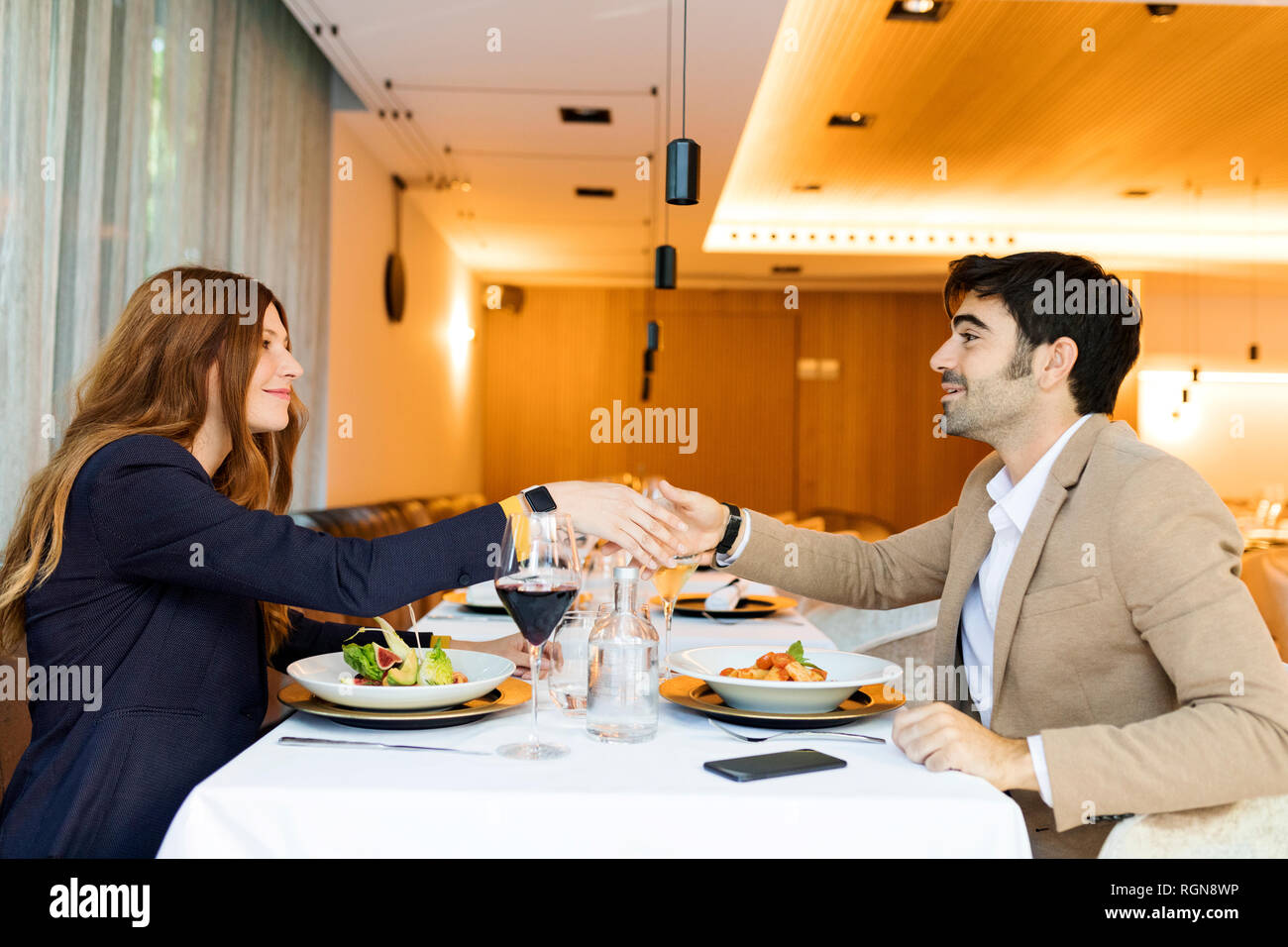 Smiling man and woman shaking hands in a restaurant Stock Photo - Alamy