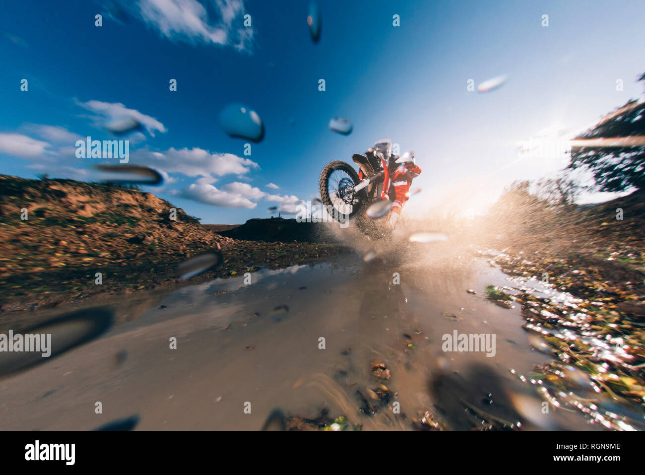 Motocross driver driving through the water, splashing Stock Photo - Alamy