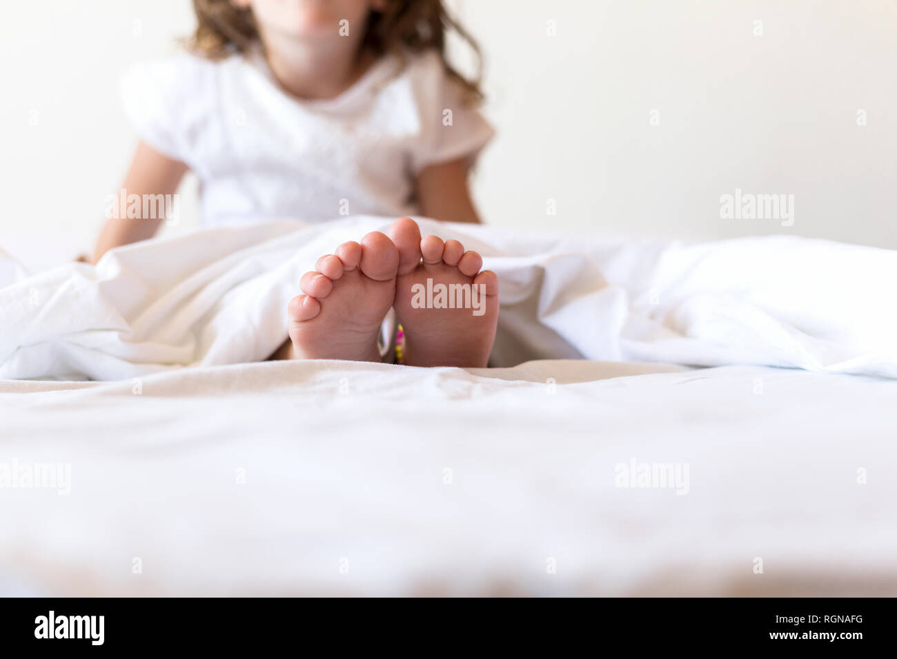 Feet of girl sitting in bed Stock Photo - Alamy